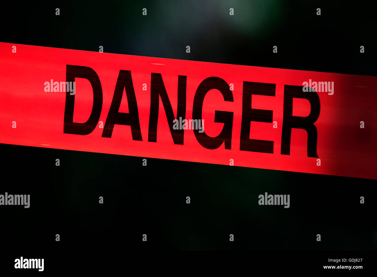 Red Danger caution tape on black background Stock Photo - Alamy