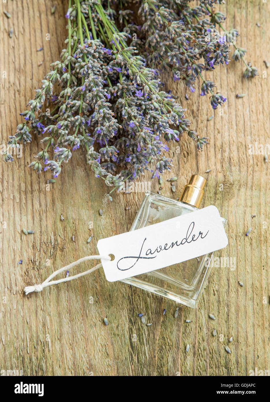 Lavender perfume in a bottle with lavender flowers and label on wooden ...