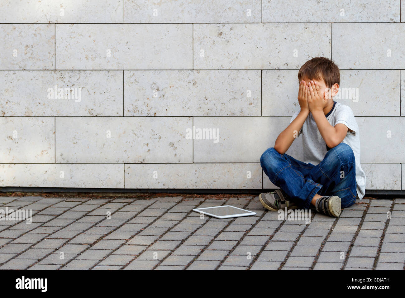 Little boy sad, tired and stressed with tablet computer PC. Kid sitting ...