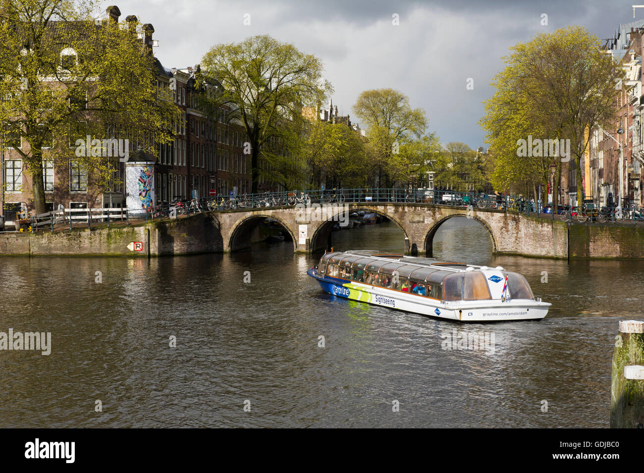 A cruising pleasure boat with tourists on the canal in Amsterdam ...