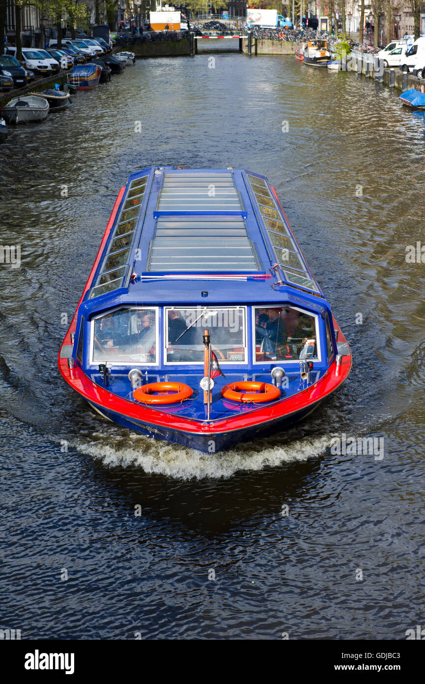 A cruising pleasure boat with tourists on the canal in Amsterdam ...