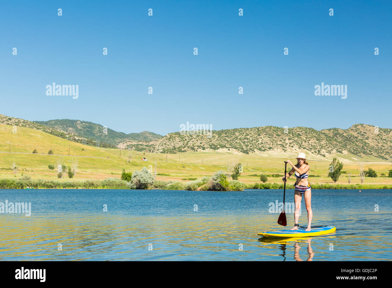 Young woman learning how to paddleboard on small pond Stock Photo - Alamy