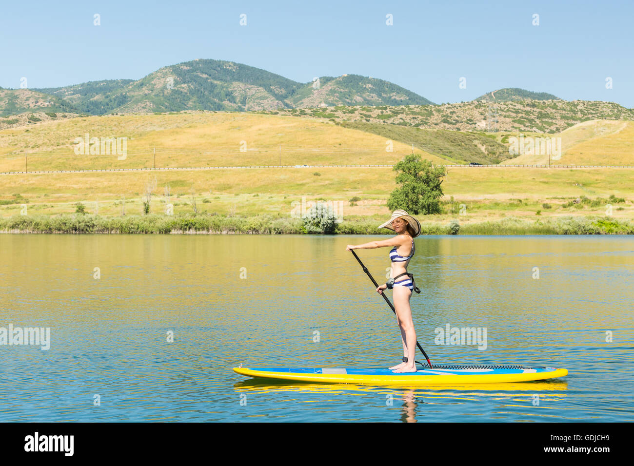 Young woman learning how to paddleboard on small pond Stock Photo - Alamy