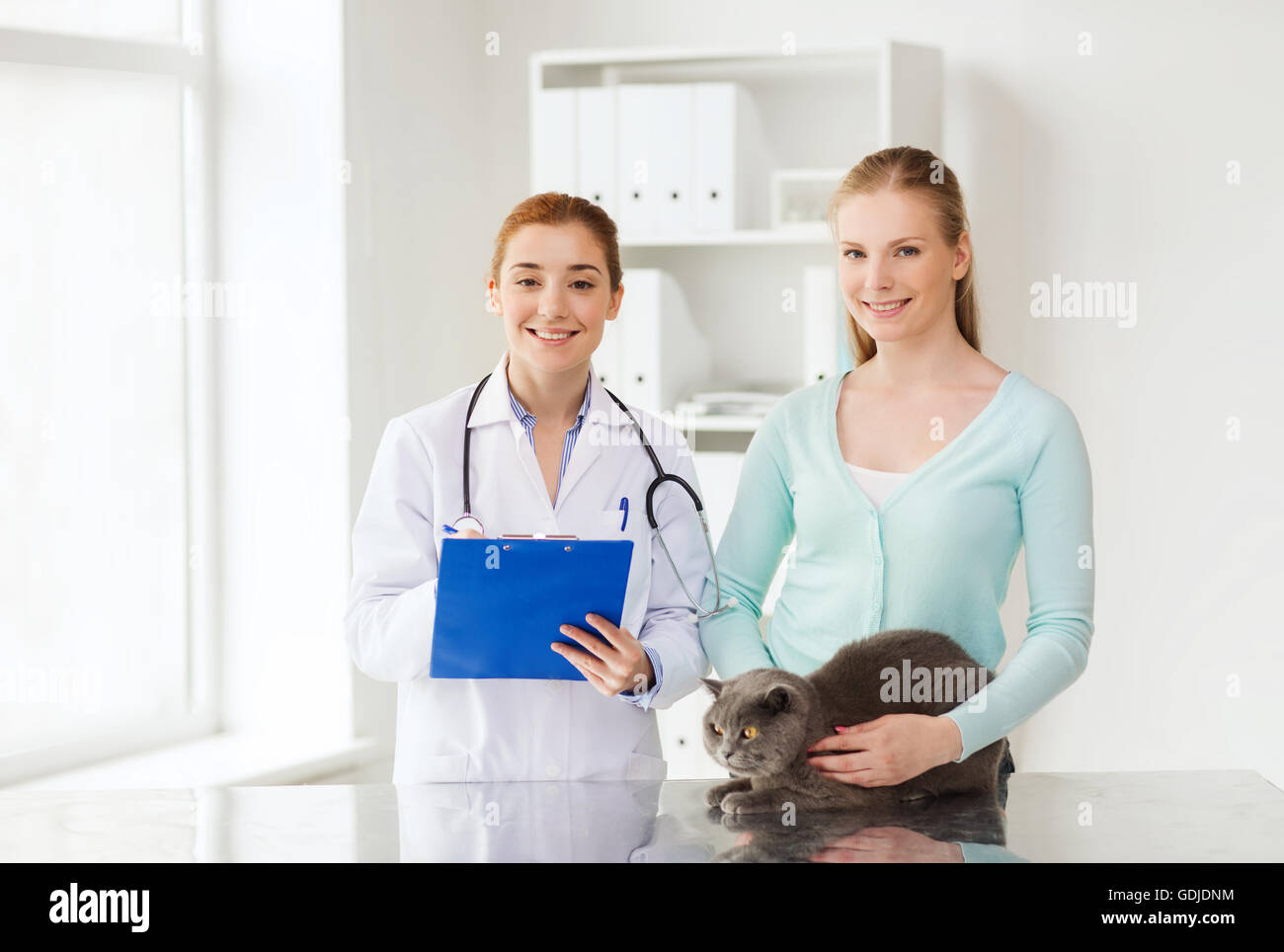 happy woman with cat and doctor at vet clinic Stock Photo - Alamy