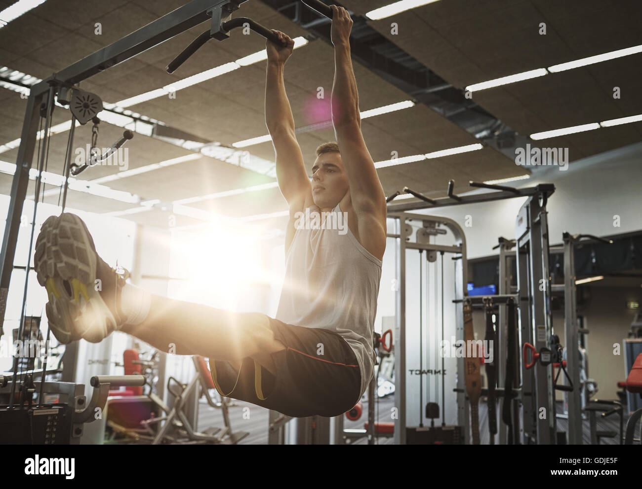man flexing abdominal muscles on pull-up bar Stock Photo - Alamy