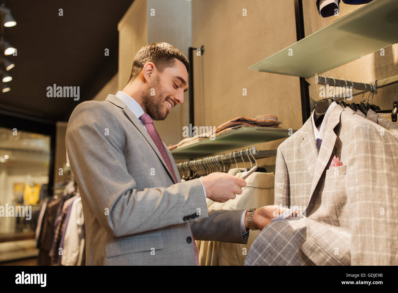 man in suit with smartphone at clothing store Stock Photo - Alamy