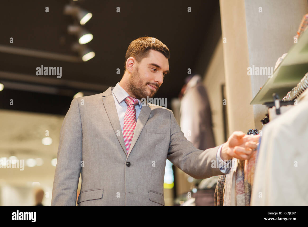 happy young man choosing clothes in clothing store Stock Photo - Alamy