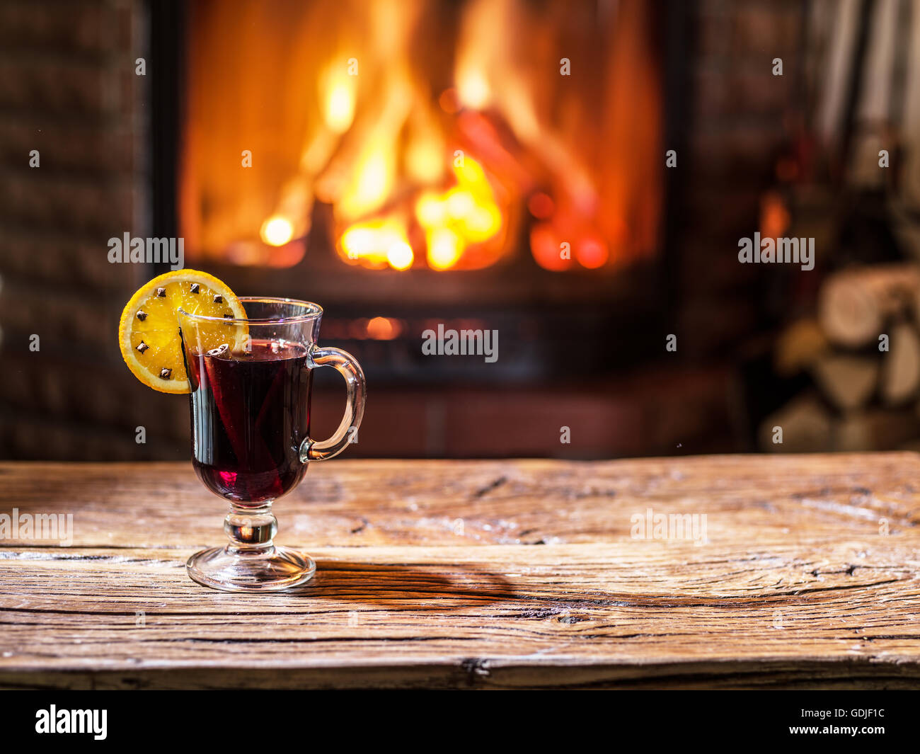 Hot mulled wine with orange slice, cloves and cinnamon stick. Fireplace ...