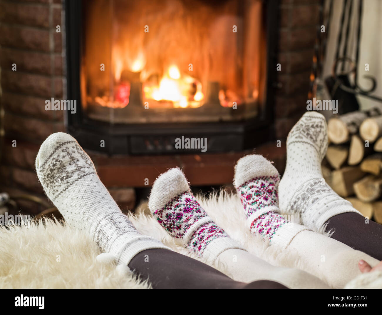 Warming and relaxing near fireplace. Woman and child feet in front of ...