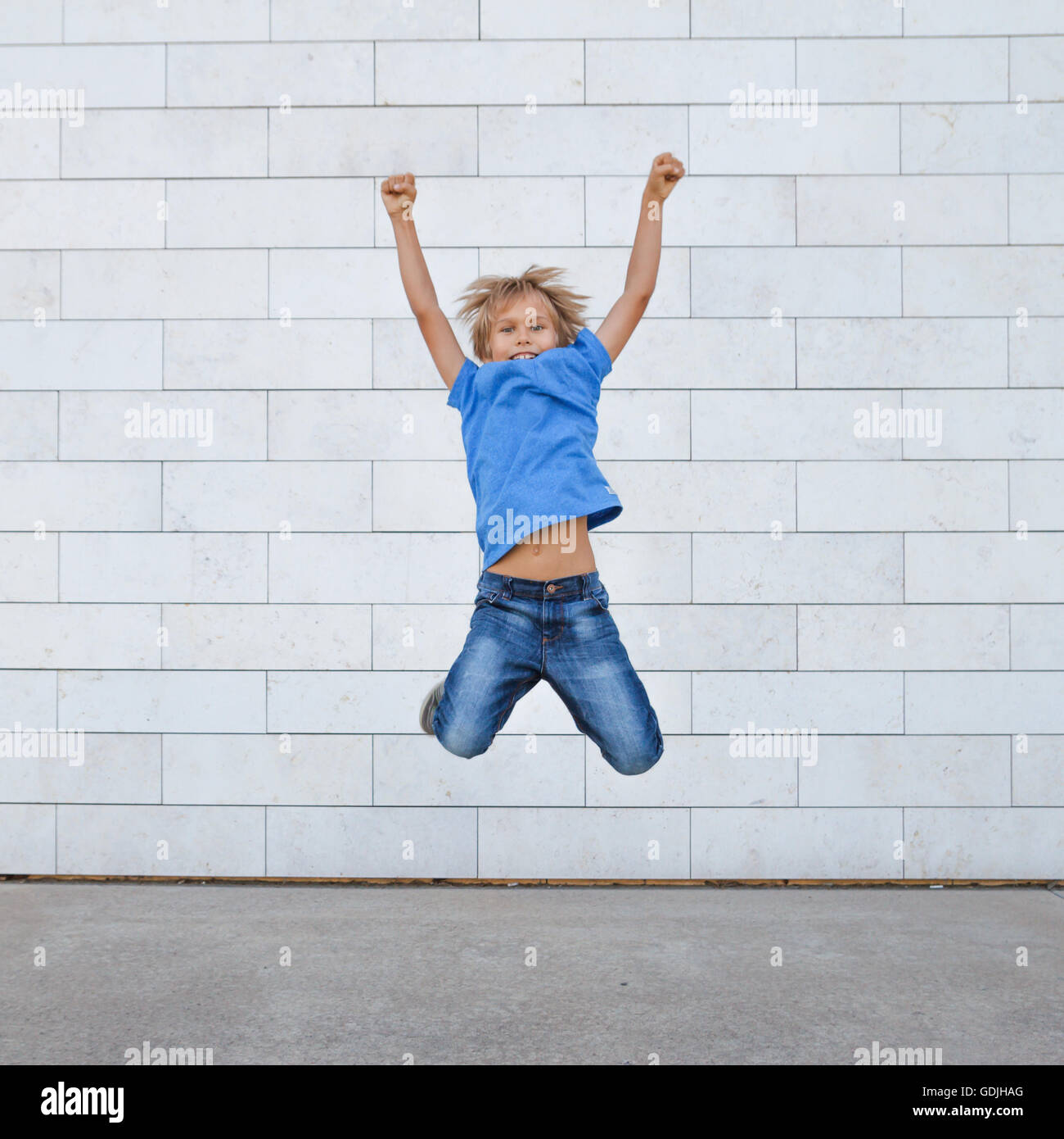 Happy little boy jumping over gray urban background. People, childhood ...