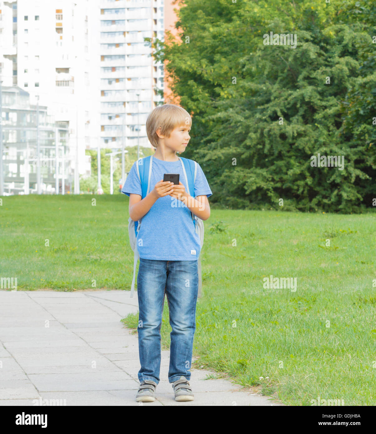 Boy with mobile phone. Child goes in the street and uses touchscreen ...
