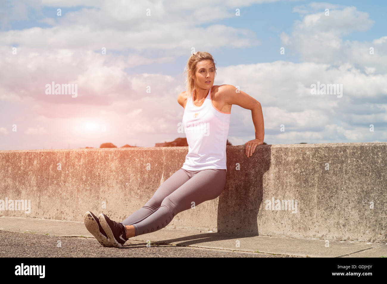 fit blonde woman doing a back press ups on a wall Stock Photo - Alamy