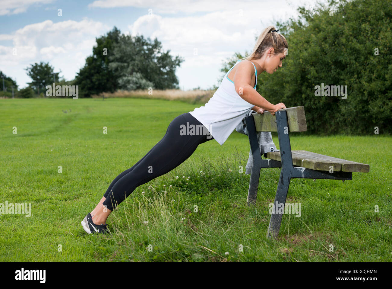 fit woman doing press ups on a park bench Stock Photo - Alamy