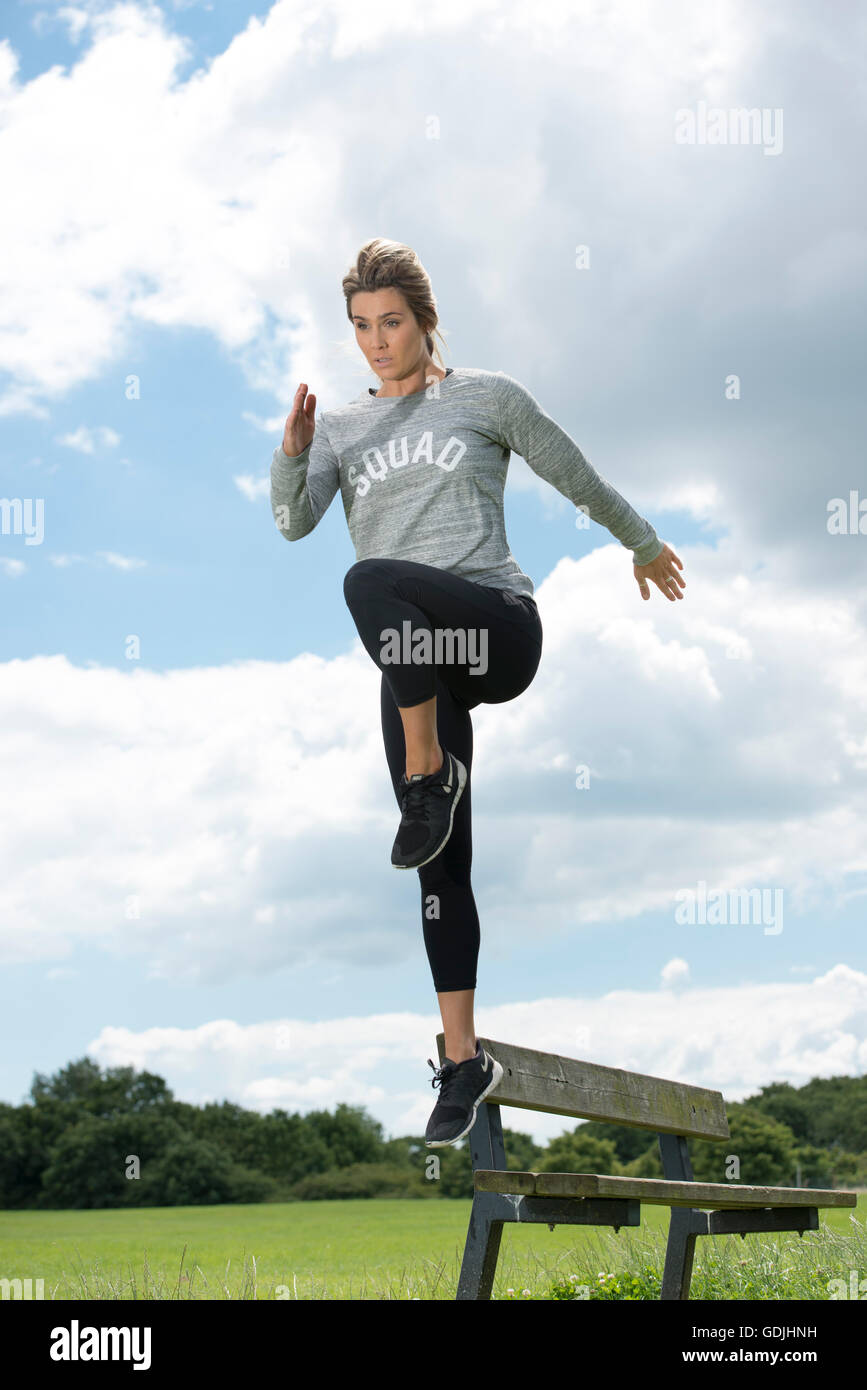 fit woman leaping over a park bench while exercising Stock Photo - Alamy