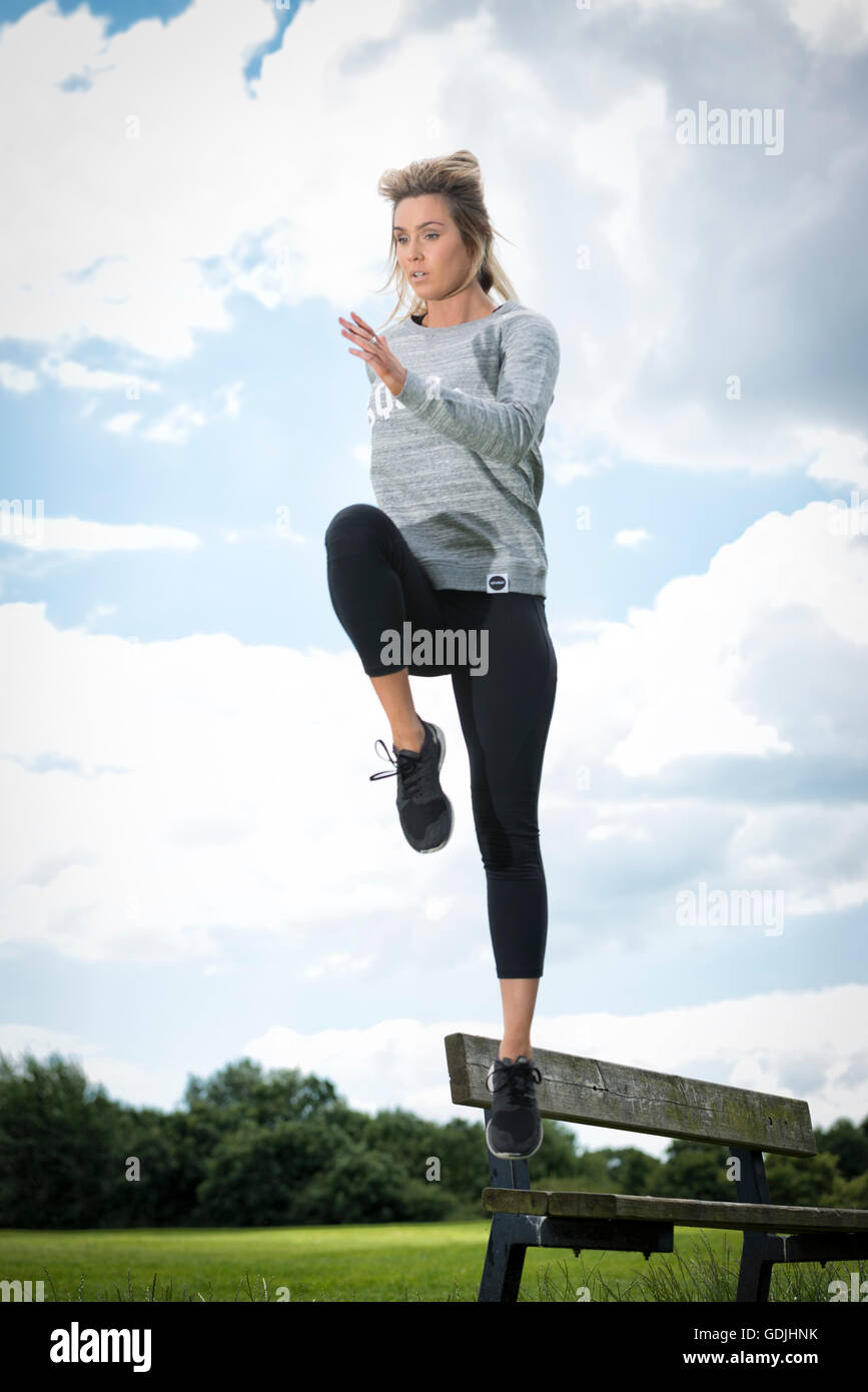 fit woman leaping over a park bench while exercising Stock Photo - Alamy