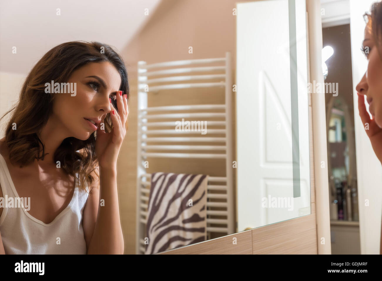 A beautiful young woman being sad at the mirror in the bathroom Stock ...