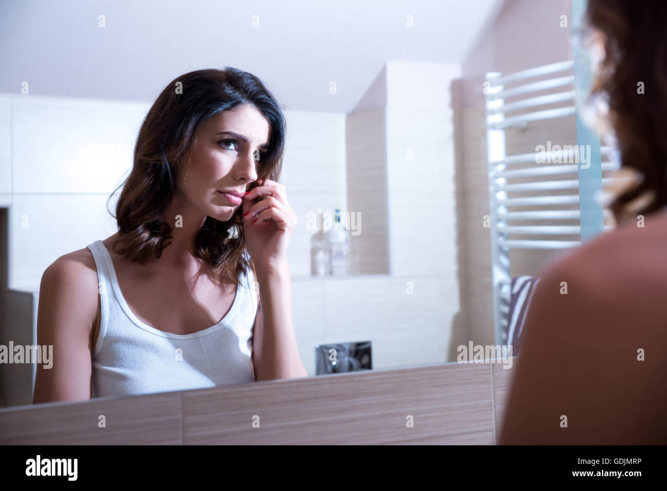 A beautiful young woman being sad at the mirror in the bathroom Stock ...