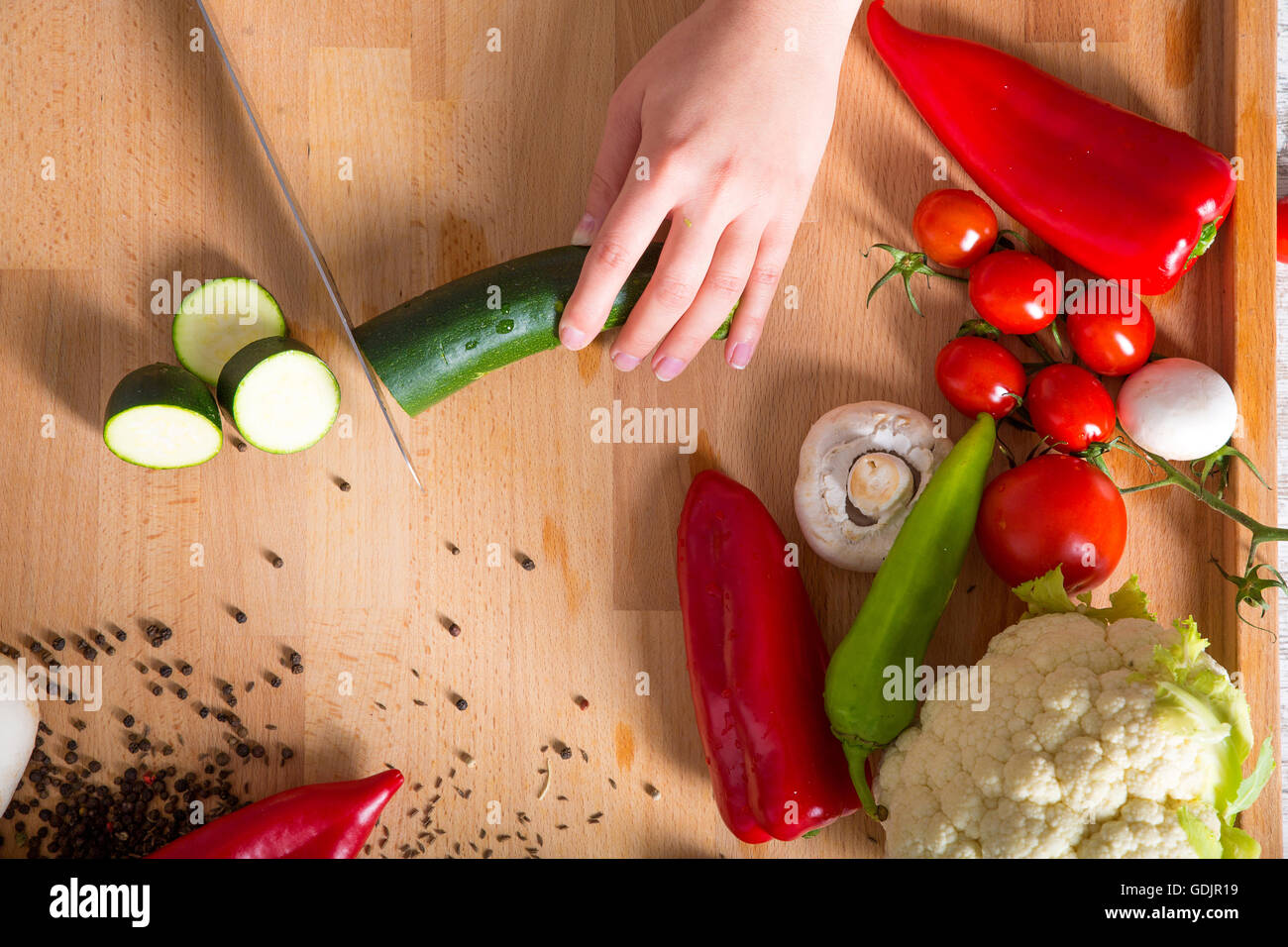 A woman chopping up vegetables at a table Stock Photo - Alamy