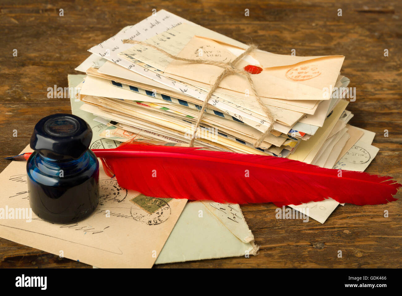 Red quill feather and ink well lying on an old table with nostalgic ...