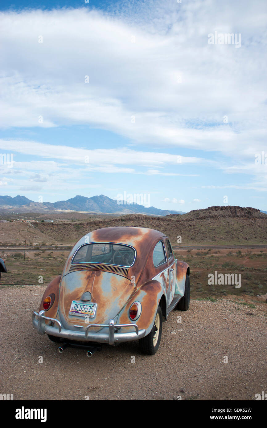 A rusty vintage Volkswagen Beetle parked on a barren desert landscape ...