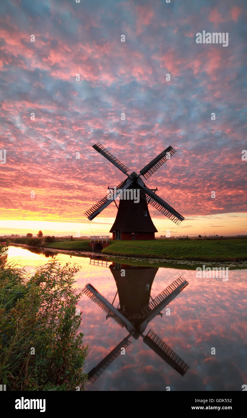 Dutch windmill and dramatic red sunrise by river, Netherlands Stock ...