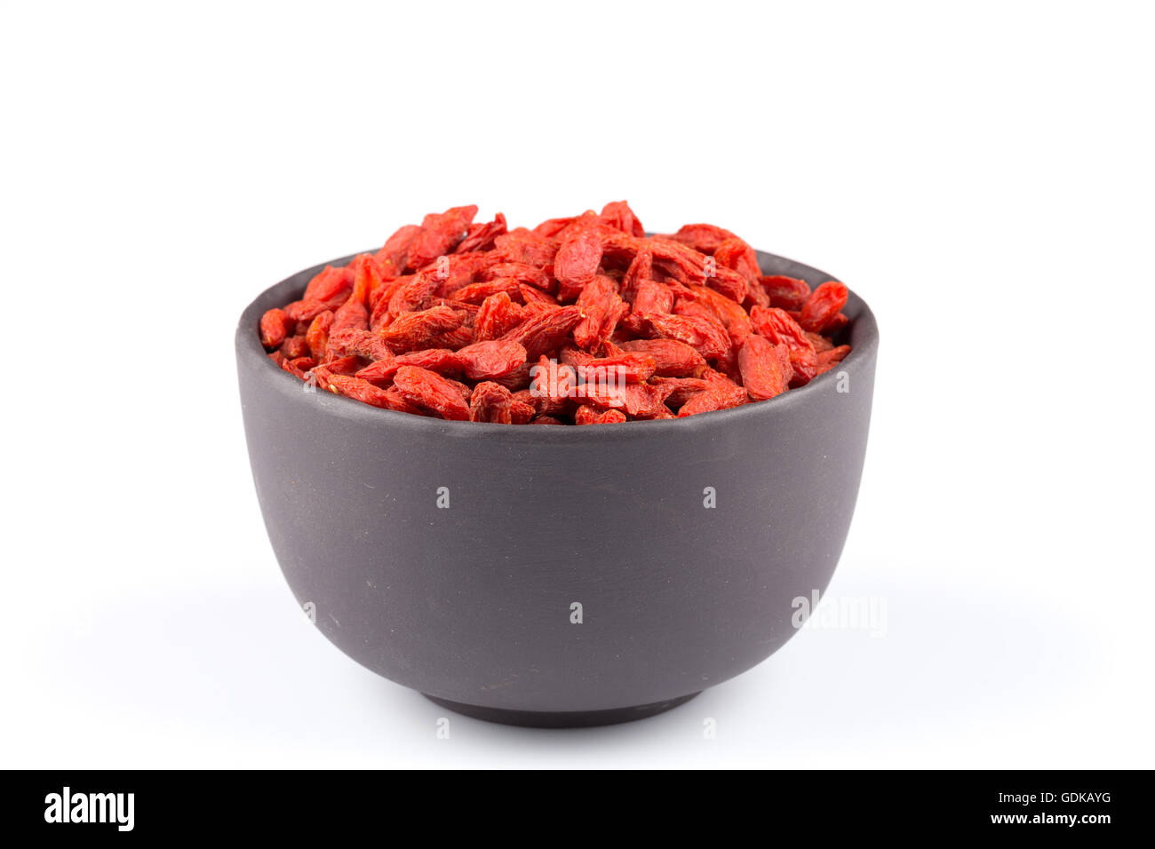 Chinese goji berries in dark stone bowl close up on white background ...