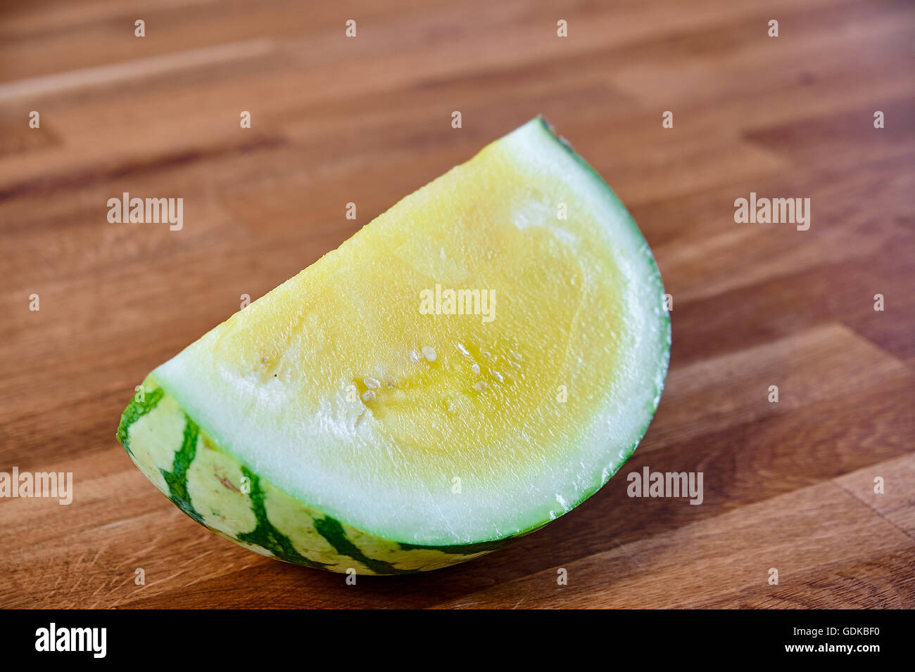 Yellow watermelon slice, lying on a table of dark brown laminated ...