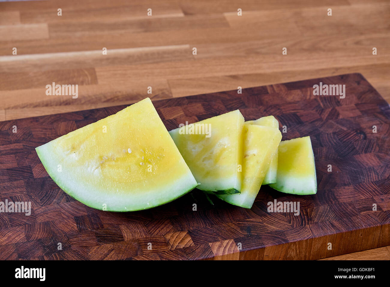Yellow watermelon slice, lying on a table of dark brown laminated ...