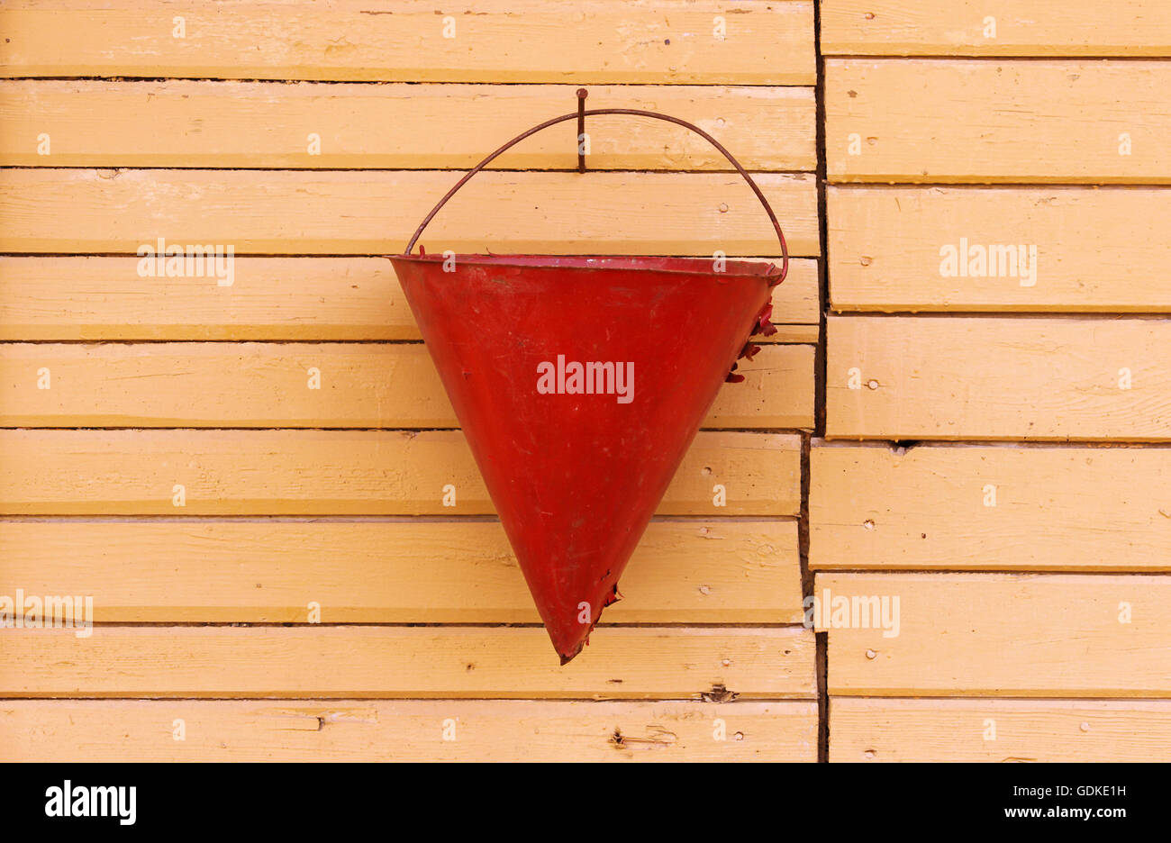 single red fire bucket hanging on the pink wall Stock Photo - Alamy