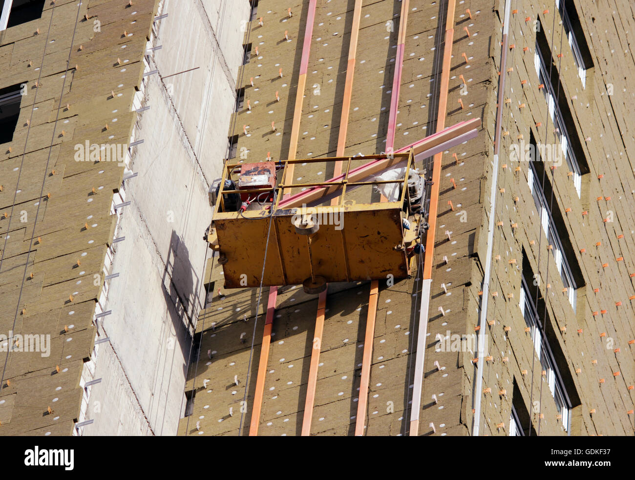 construction suspended yellow cradle with workers on a newly built high ...