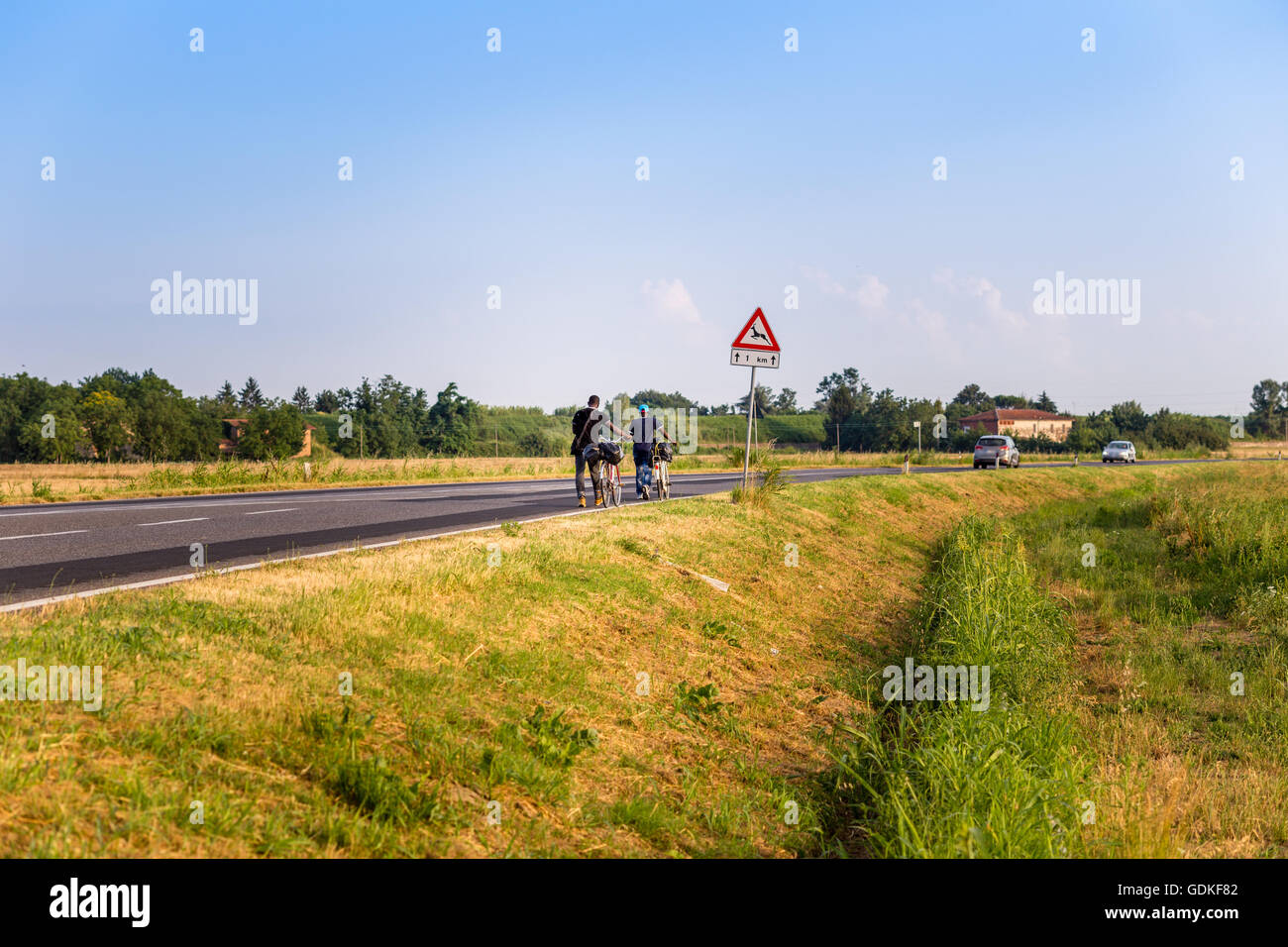 cyclists walking on a highway with the bicycle at their side Stock ...