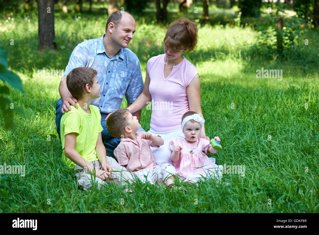 happy family portrait on outdoor, group of five people sit on grass in ...