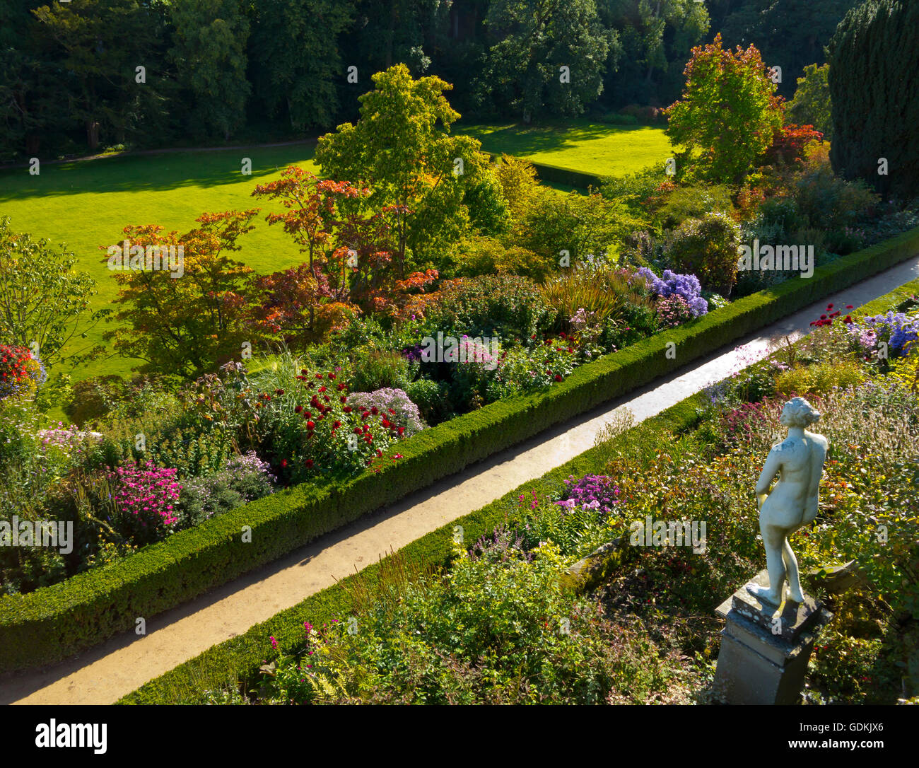 View looking down on path trough formal gardens with summer borders and ...
