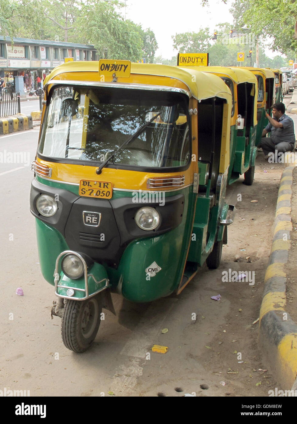 A series of rickshaws stand in a parking lot in while the waiting for ...