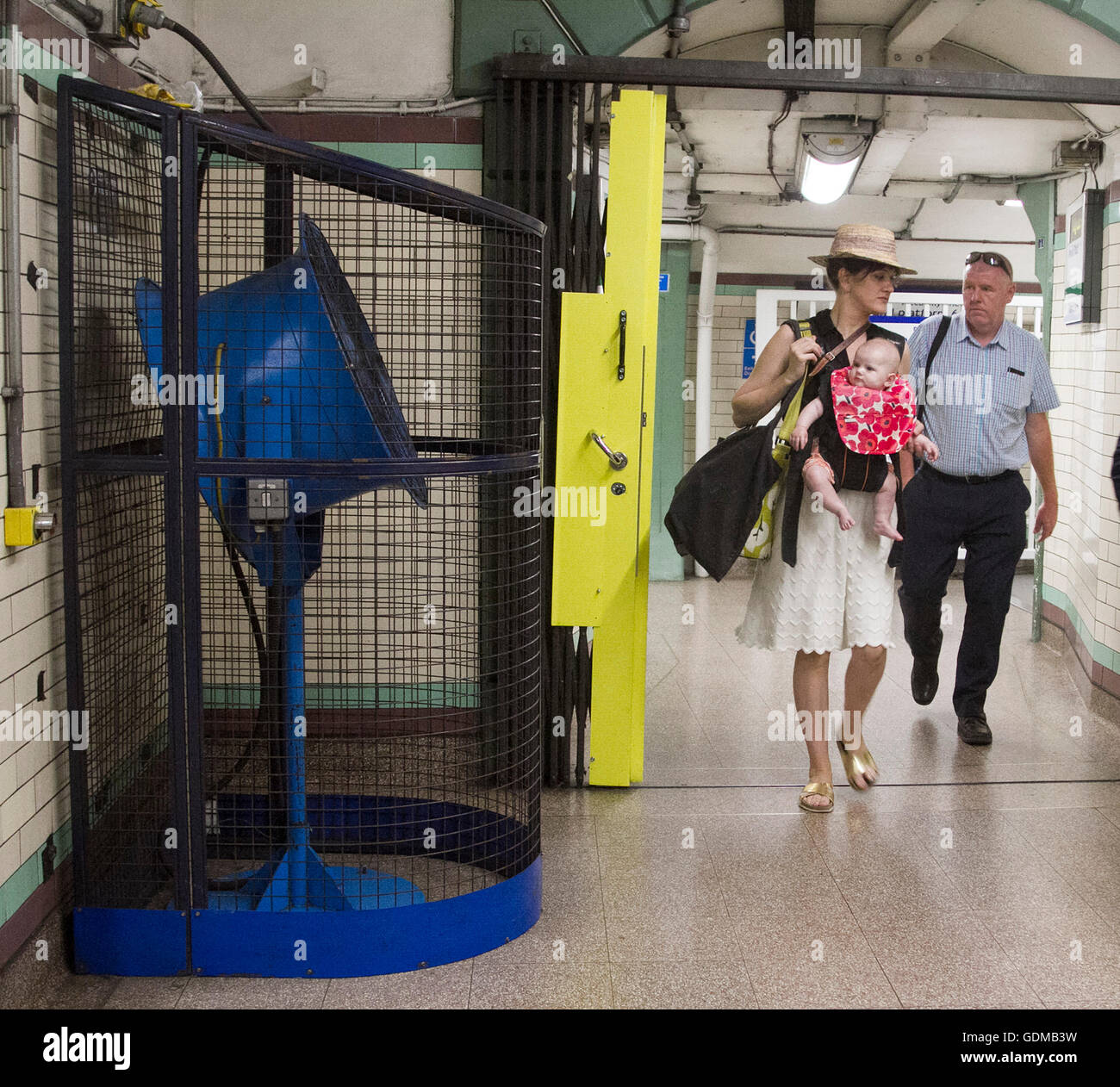 London,19th July 2016. A mother with a baby walks past a large fan ...