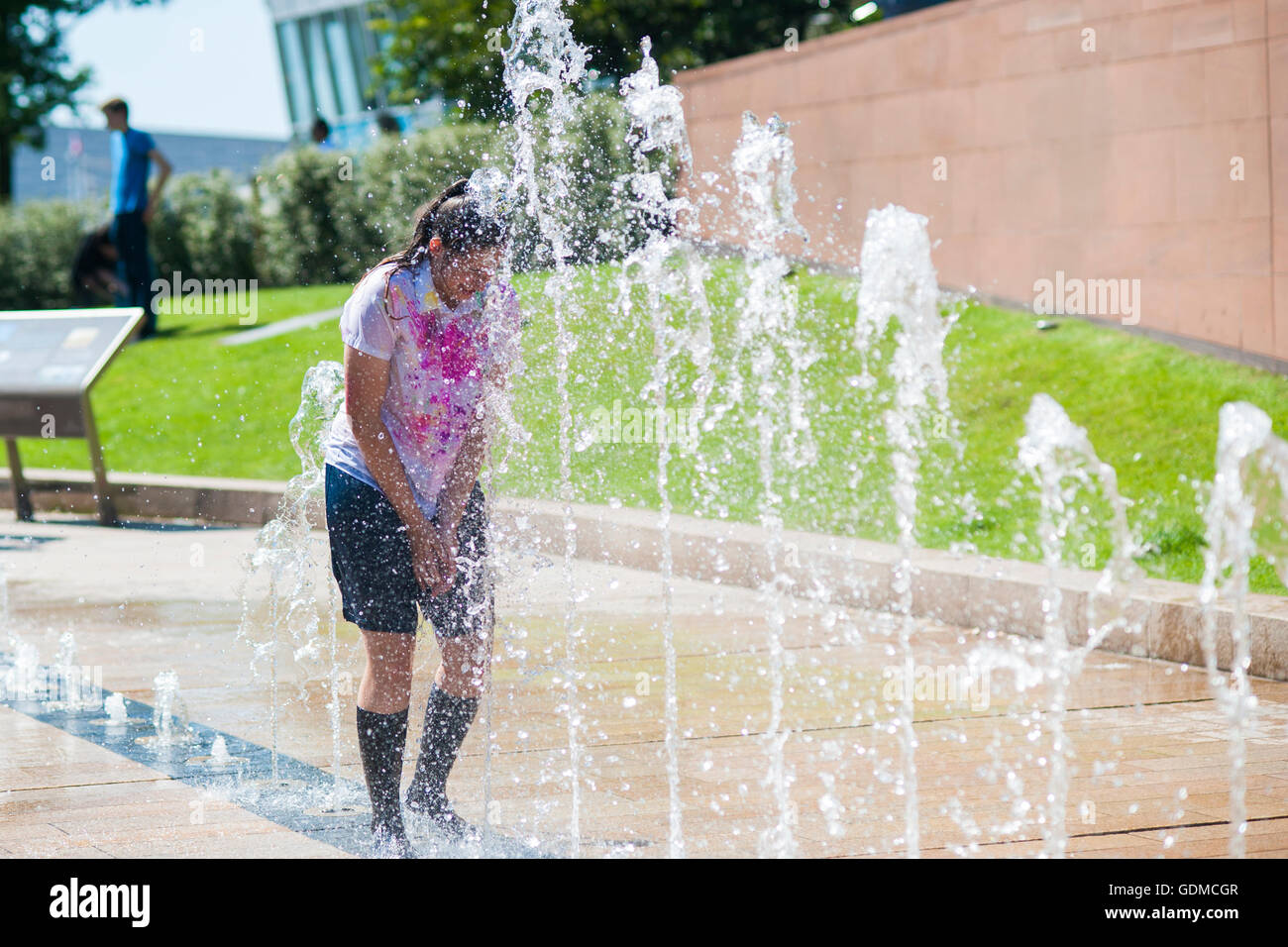 Liverpool, UK. 19th July 2016. A schoolgirl runs into a water fountain ...