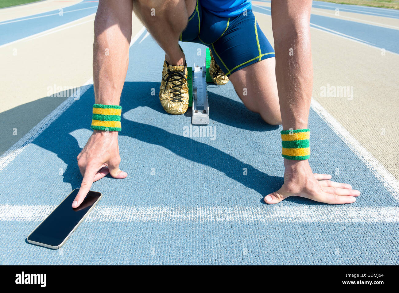 Athlete crouching at the starting line of a running track wearing ...