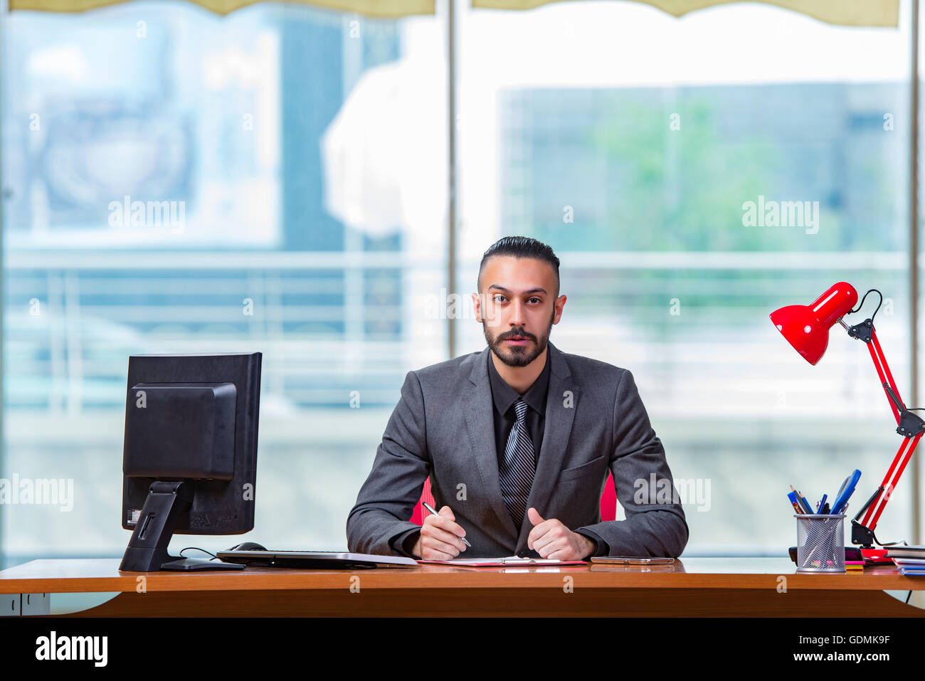 Happy businessman sitting at the desk Stock Photo - Alamy