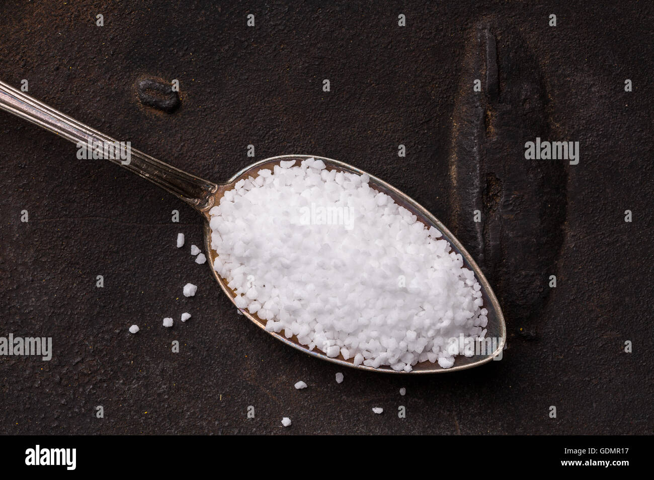 Salt on old spoon and old metal background. View from above. Closeup ...