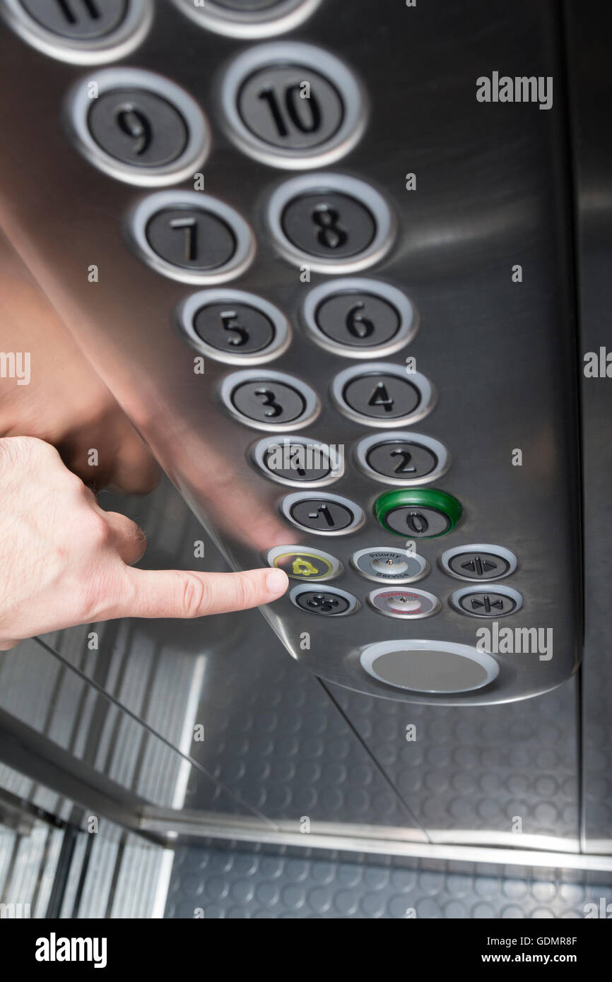 Forefinger pressing the alarm button in the elevator – top down view ...