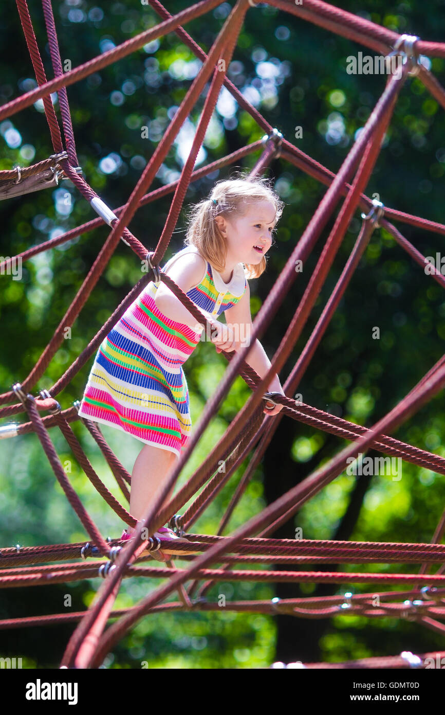 Active little child playing on climbing net and jumping on trampoline ...