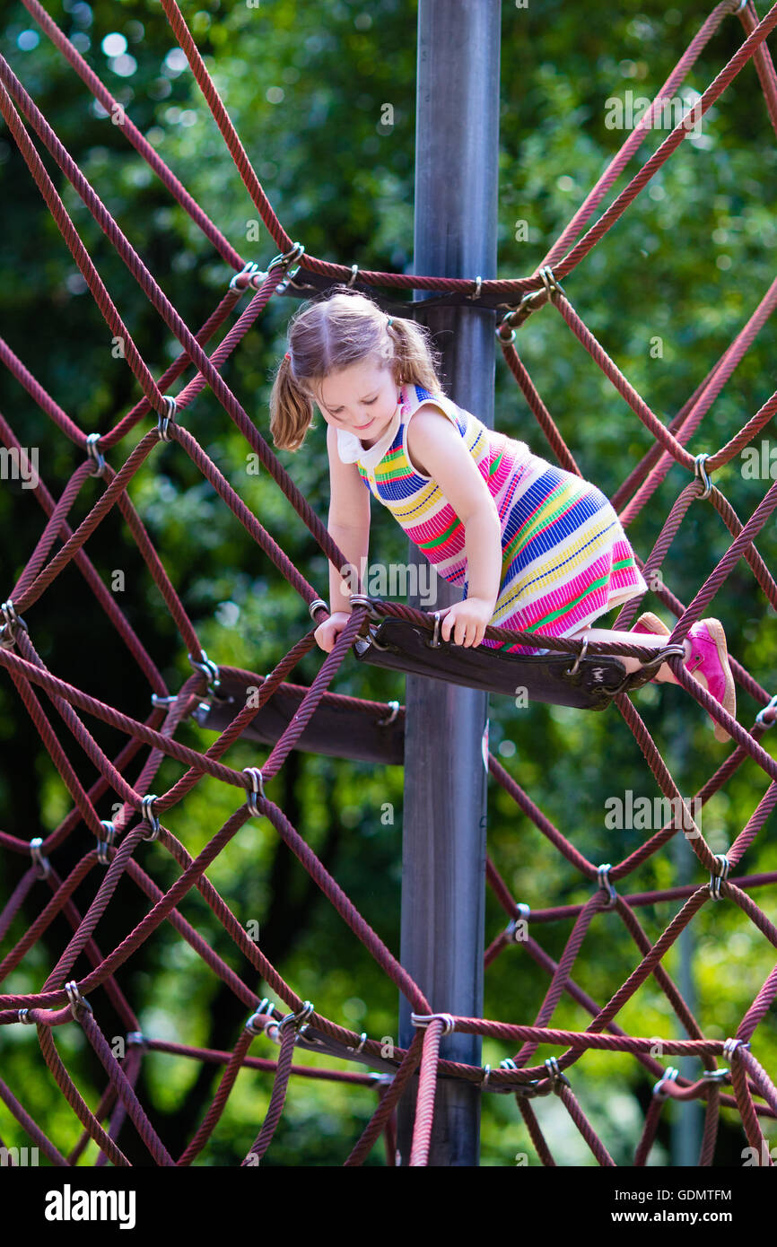 Active little child playing on climbing net and jumping on trampoline ...