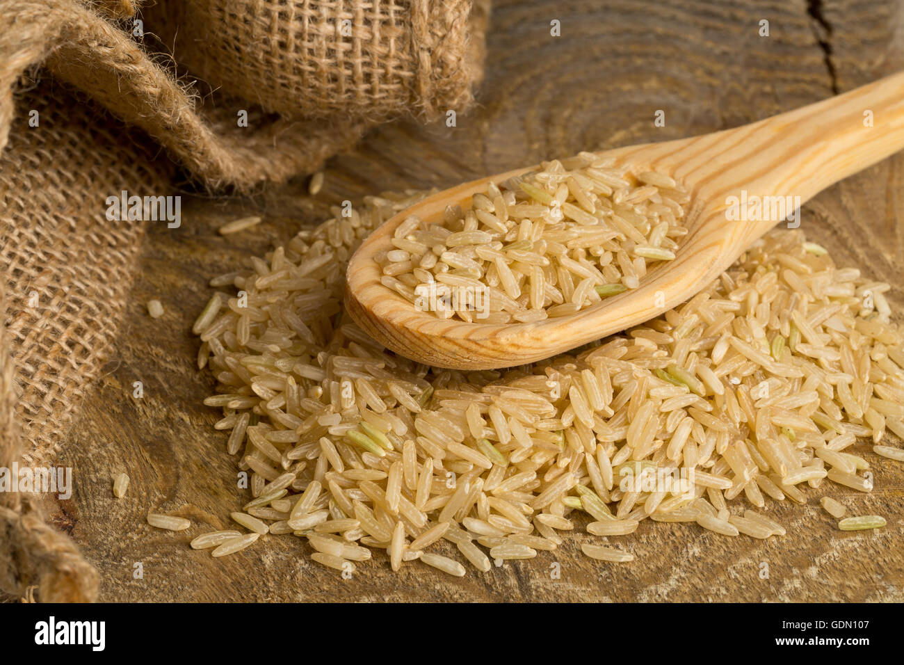 Natural brown uncooked rice in wooden spoon on wood table Stock Photo ...