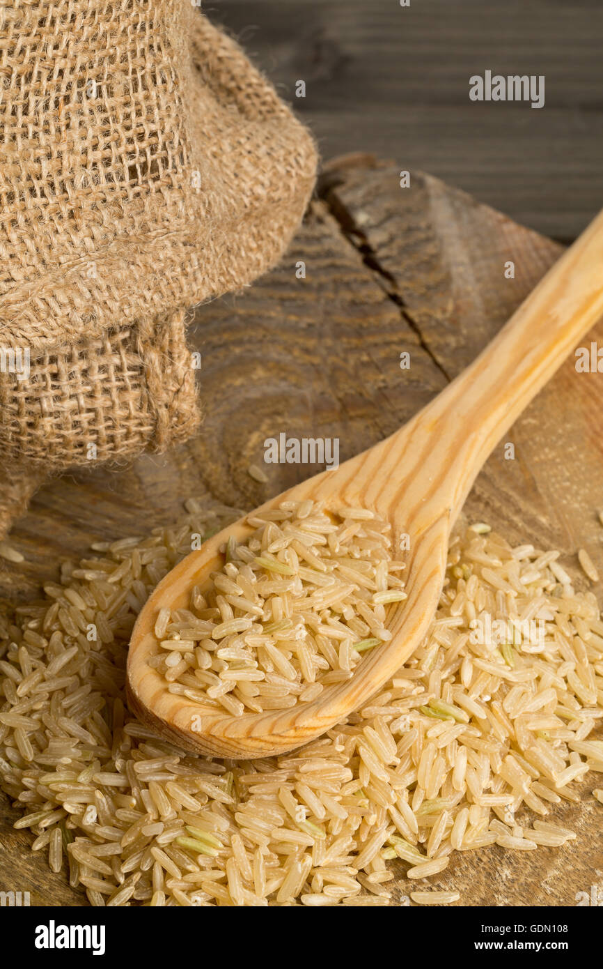 Natural brown uncooked rice in wooden spoon on wood table Stock Photo ...