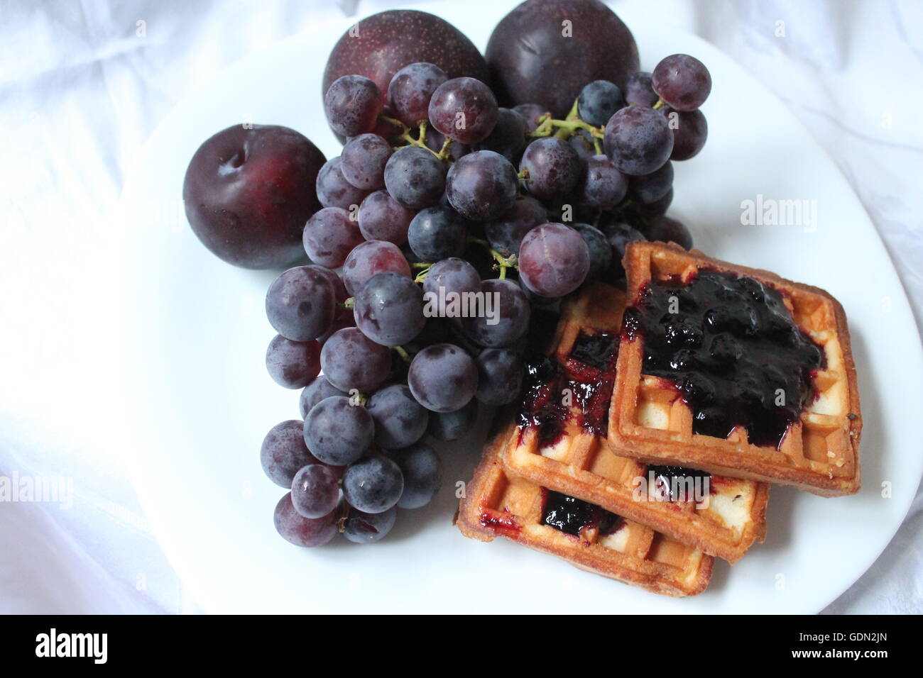 healthy breakfast from violet sweet grapes, ripe plums and waffles with ...