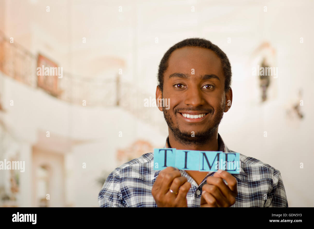 Headshot handsome man holding up small letters spelling the word time ...