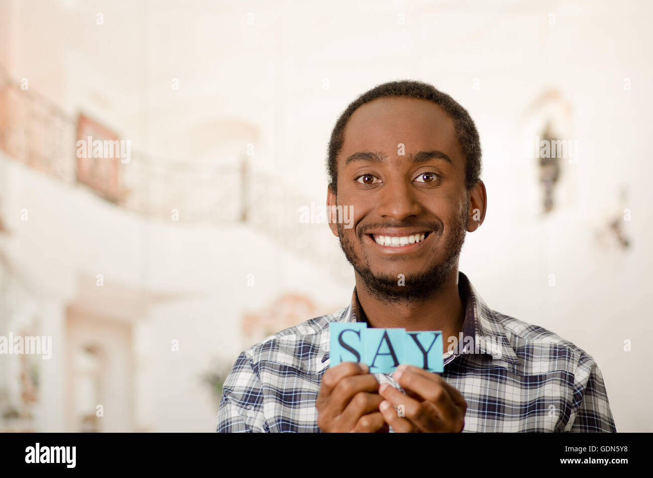 Headshot handsome man holding up small letters spelling the word say ...