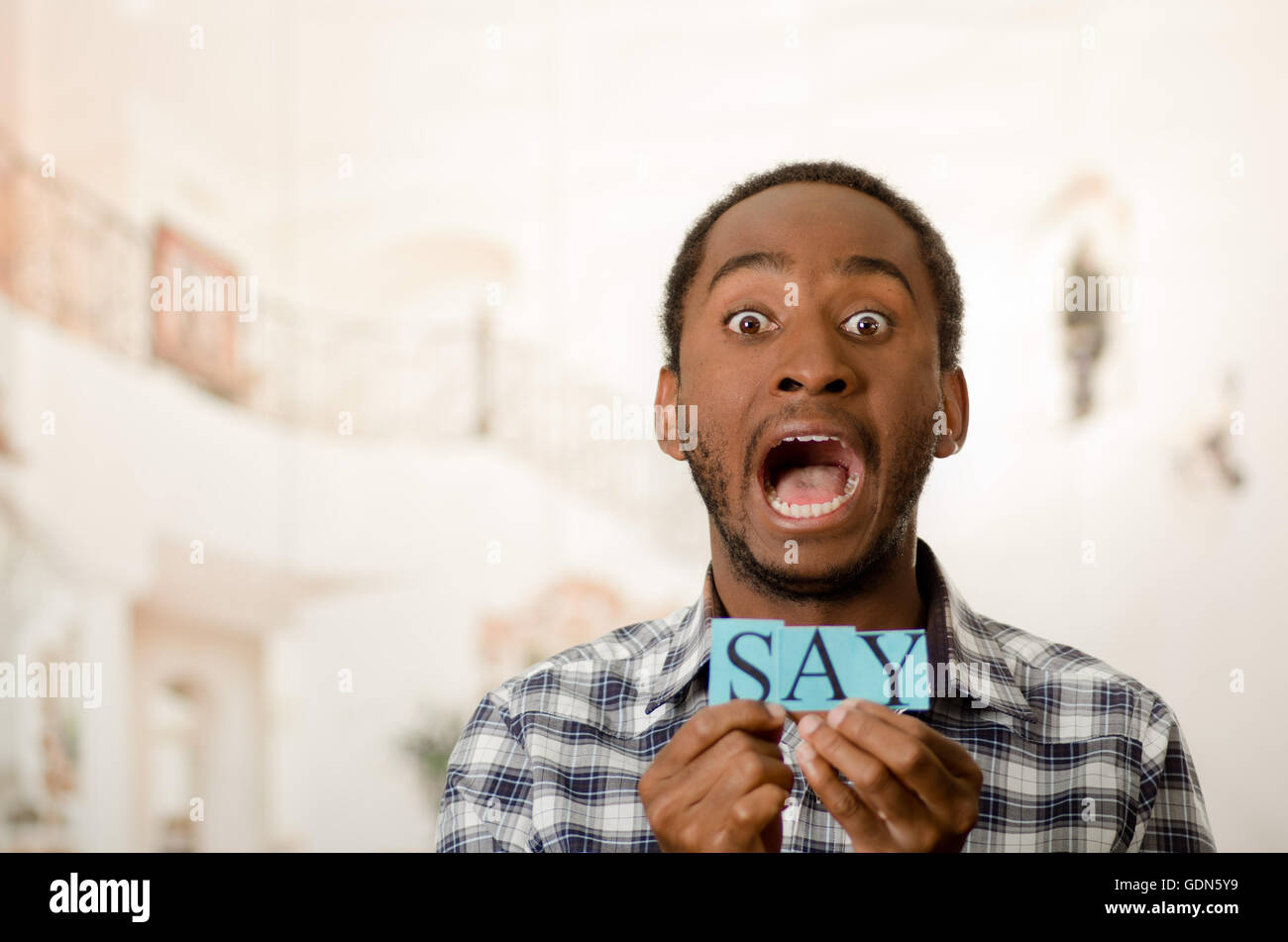 Headshot handsome man holding up small letters spelling the word say ...