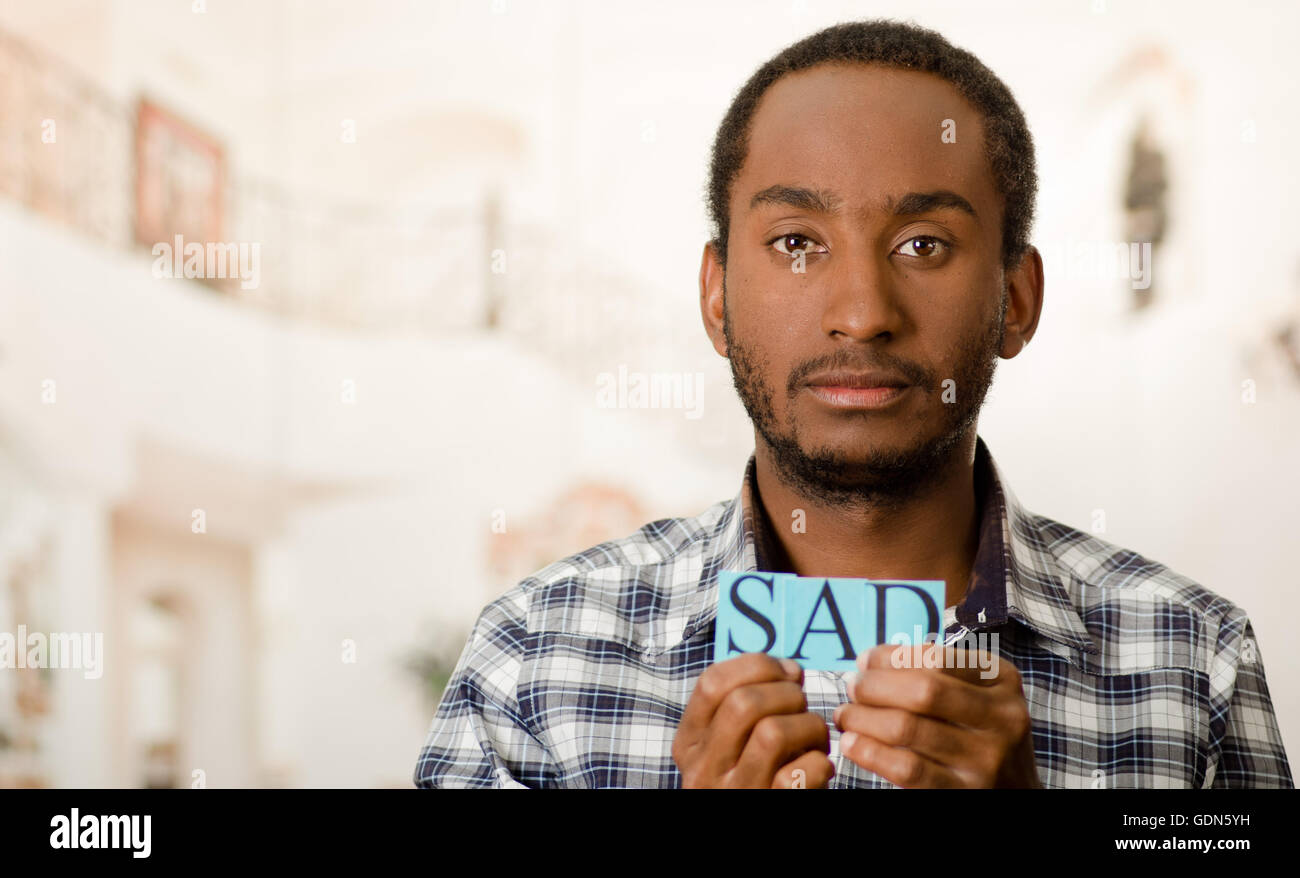 Headshot handsome man holding up small letters spelling the word sad ...