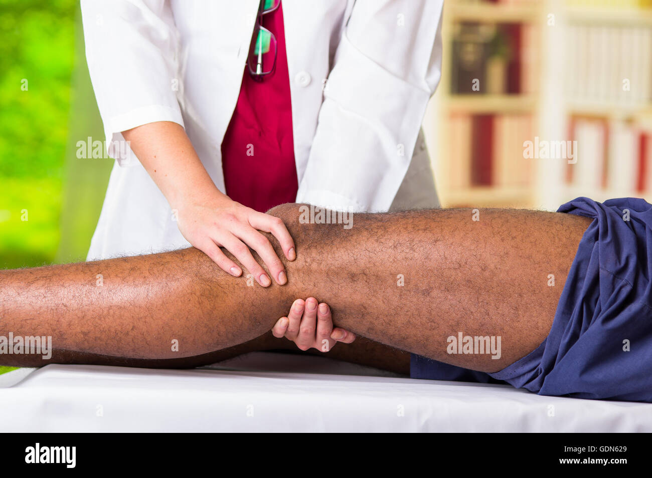 Man getting knee treatment from physio therapist, her hands holding his ...